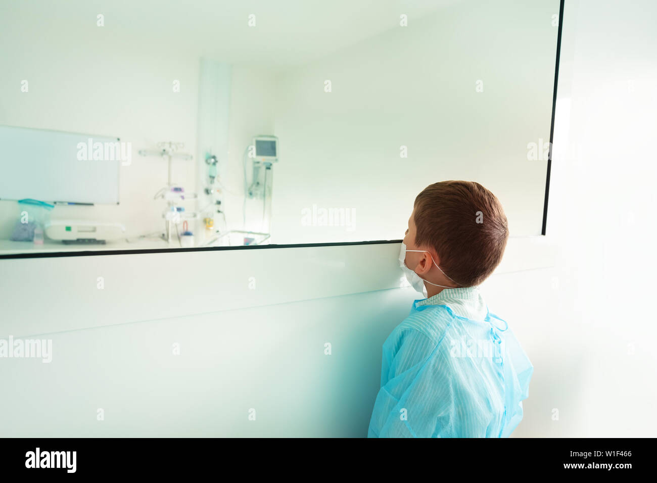 Little boy looking into operating room wearing mask worried, in ...