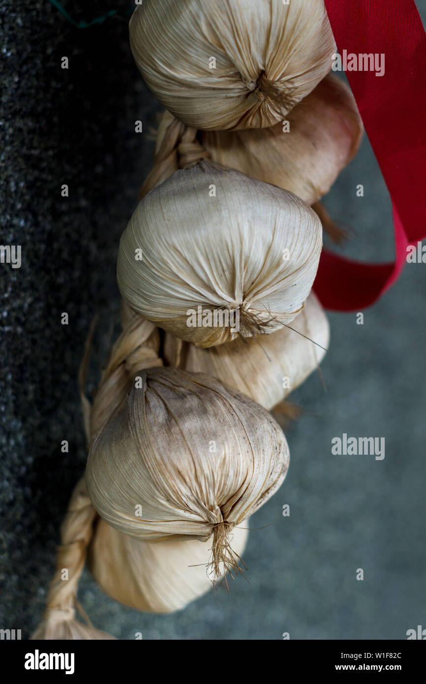 A garlic rope hanging on a wall, tied with a red ribbon Stock Photo - Alamy