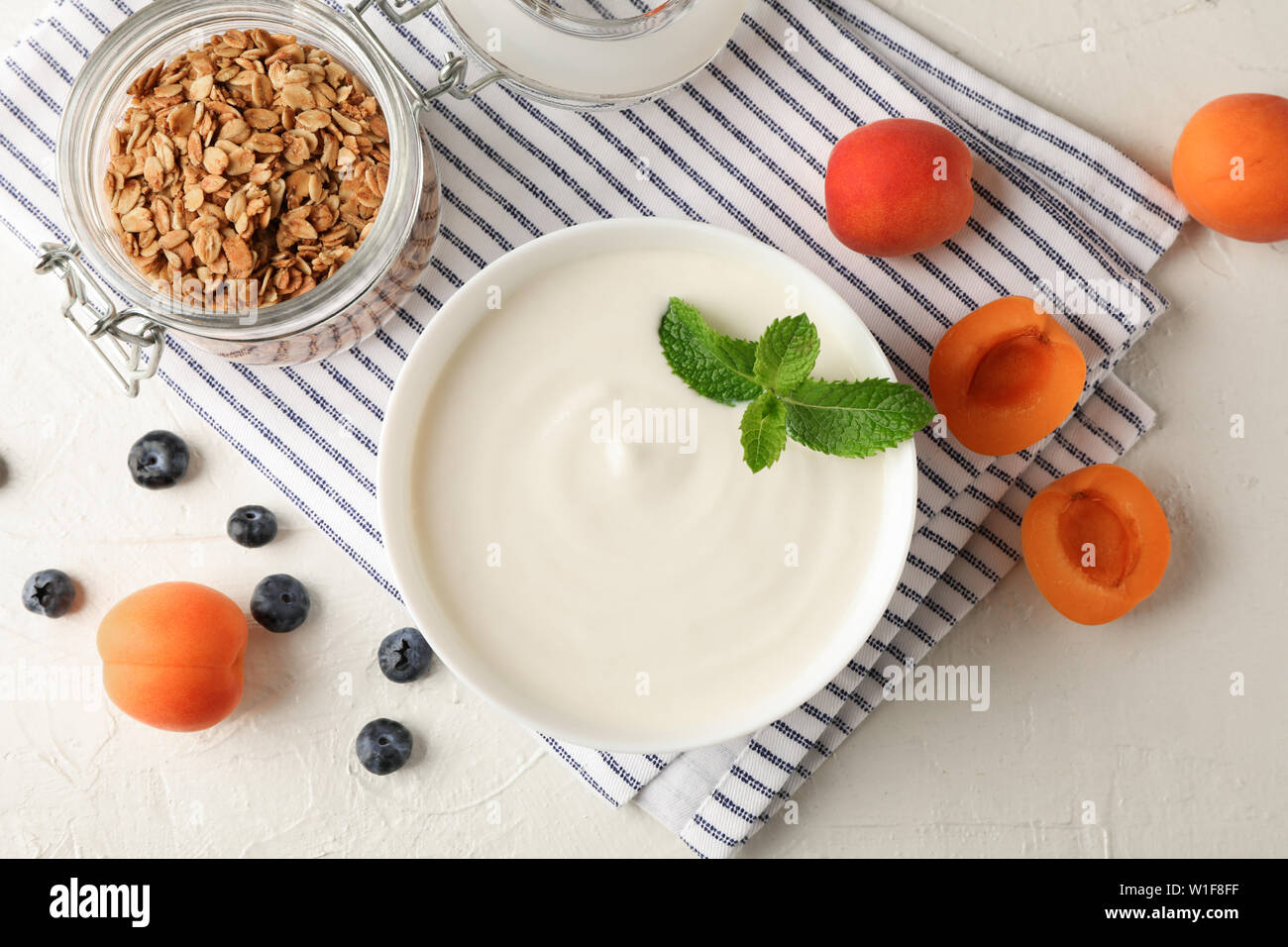 Composition with granola, yogurt and fresh fruits on white cement ...