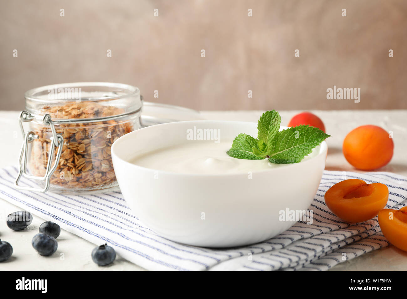Composition with granola, yogurt and fresh fruits on white cement ...
