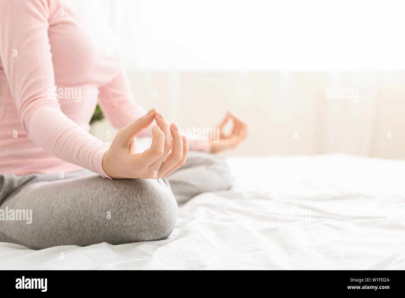 Young woman meditating in lotus position on bed Stock Photo - Alamy