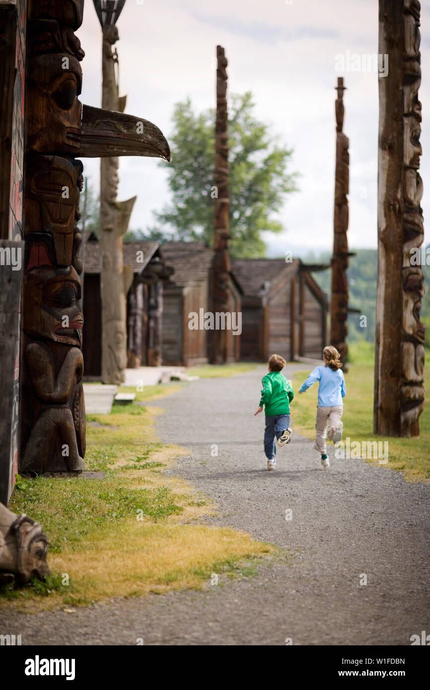 Two children running towards totem poles Stock Photo - Alamy