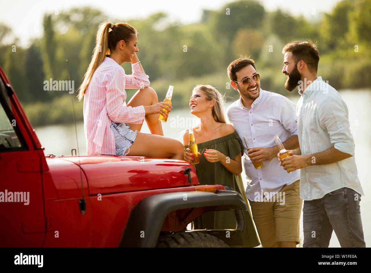 Four young people having fun in convertible car by river Stock Photo ...