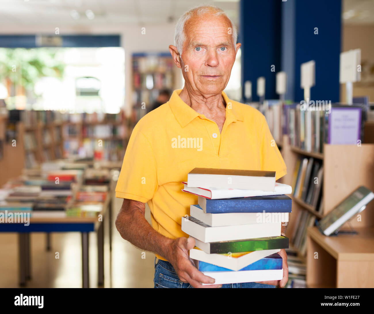 Positive senior man holding pile of books bought in bookshop Stock ...