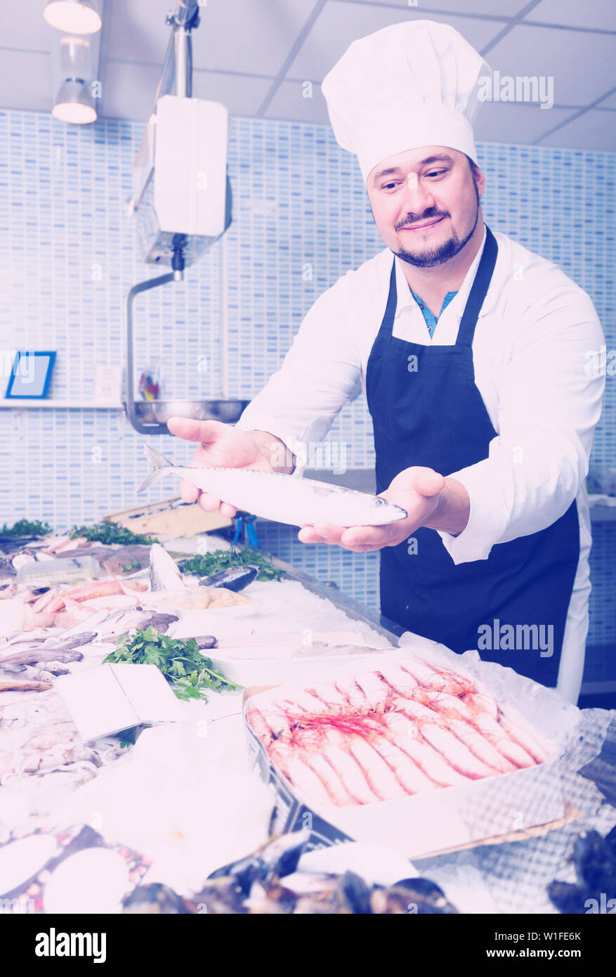Man in uniform showing fish in supermarket Stock Photo - Alamy