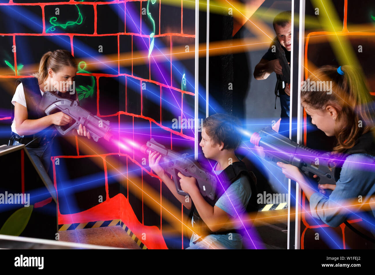 Group of positive kids and adults with laser pistols having fun on ...