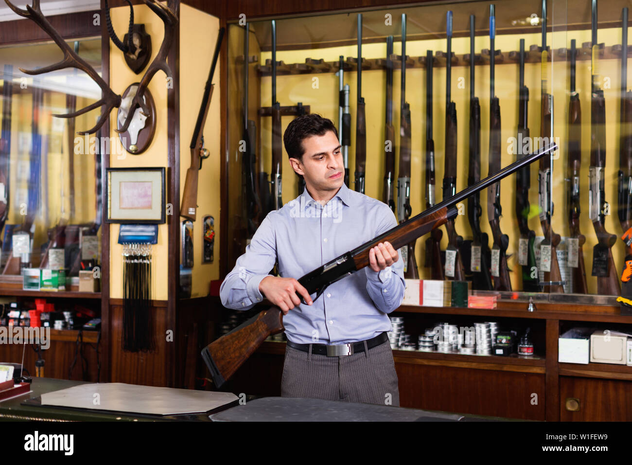 Handsome positive adult male in hunting shop with rifle in hands Stock ...