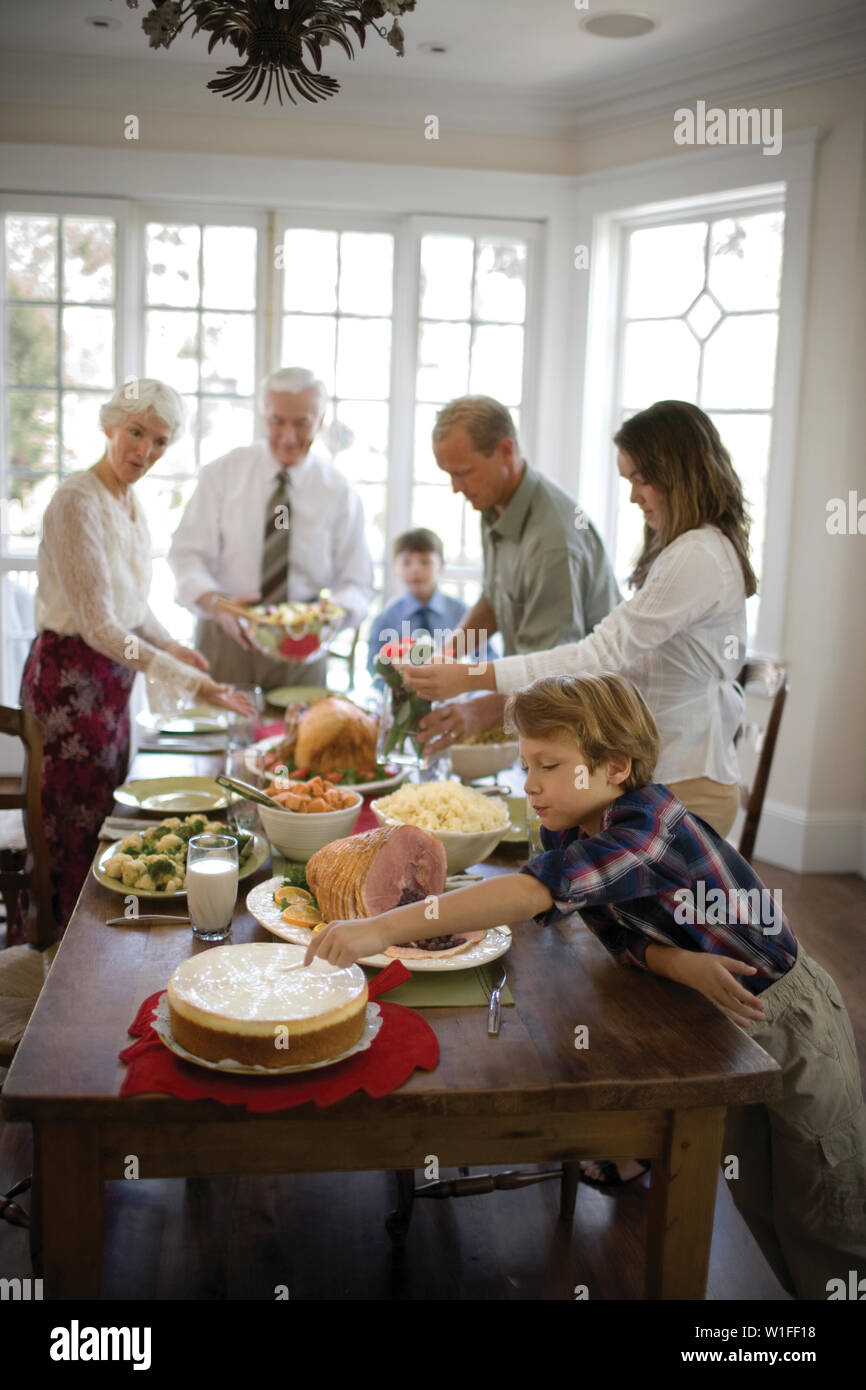 Boy touching a cake while having dinner with his extended family Stock ...