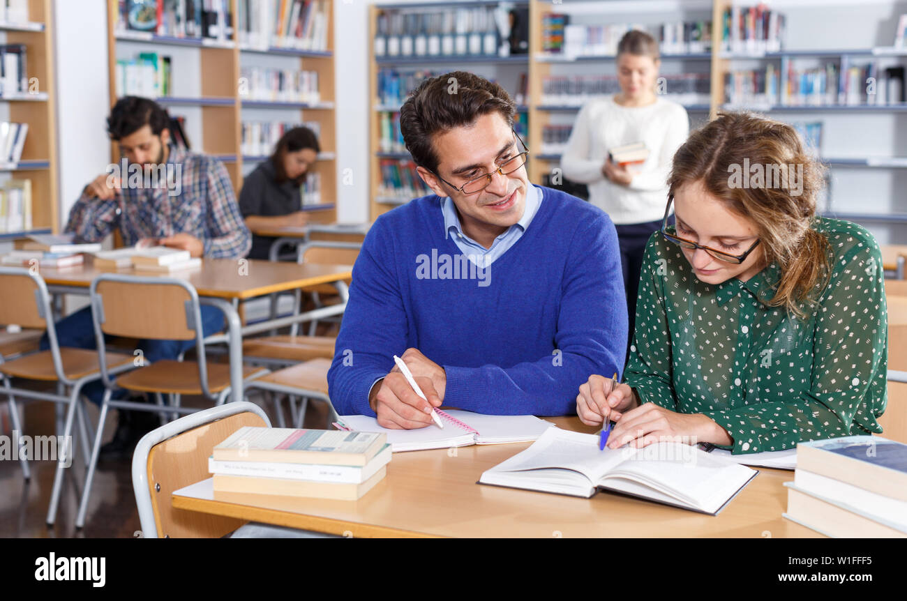 Young people reading and making notes while preparing for exam in ...
