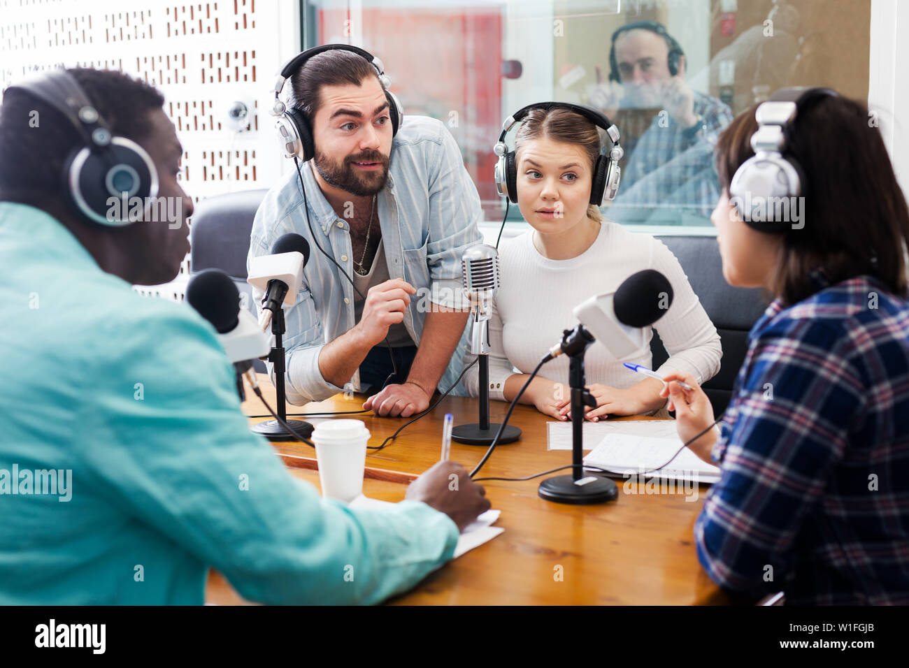 Positive male and female radio hosts interviewing guest in sound ...