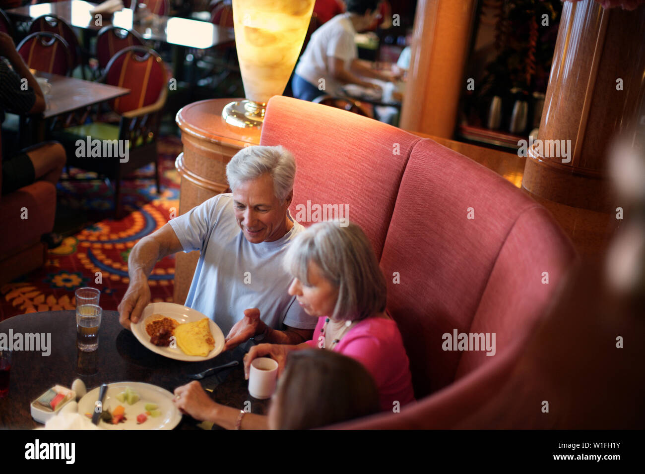 Three people sitting down in a booth having their breakfast in a ...