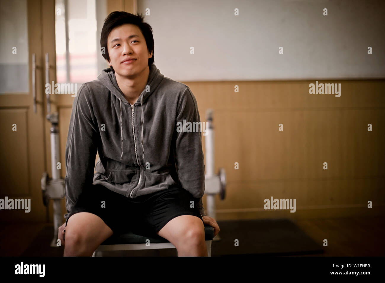 Teenage boy sitting at the end of a bench press Stock Photo - Alamy