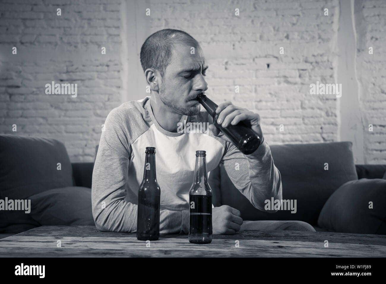 Young sad drunk men drinking beer and alcohol feeling wasted, lonely and desperate in pain and ...