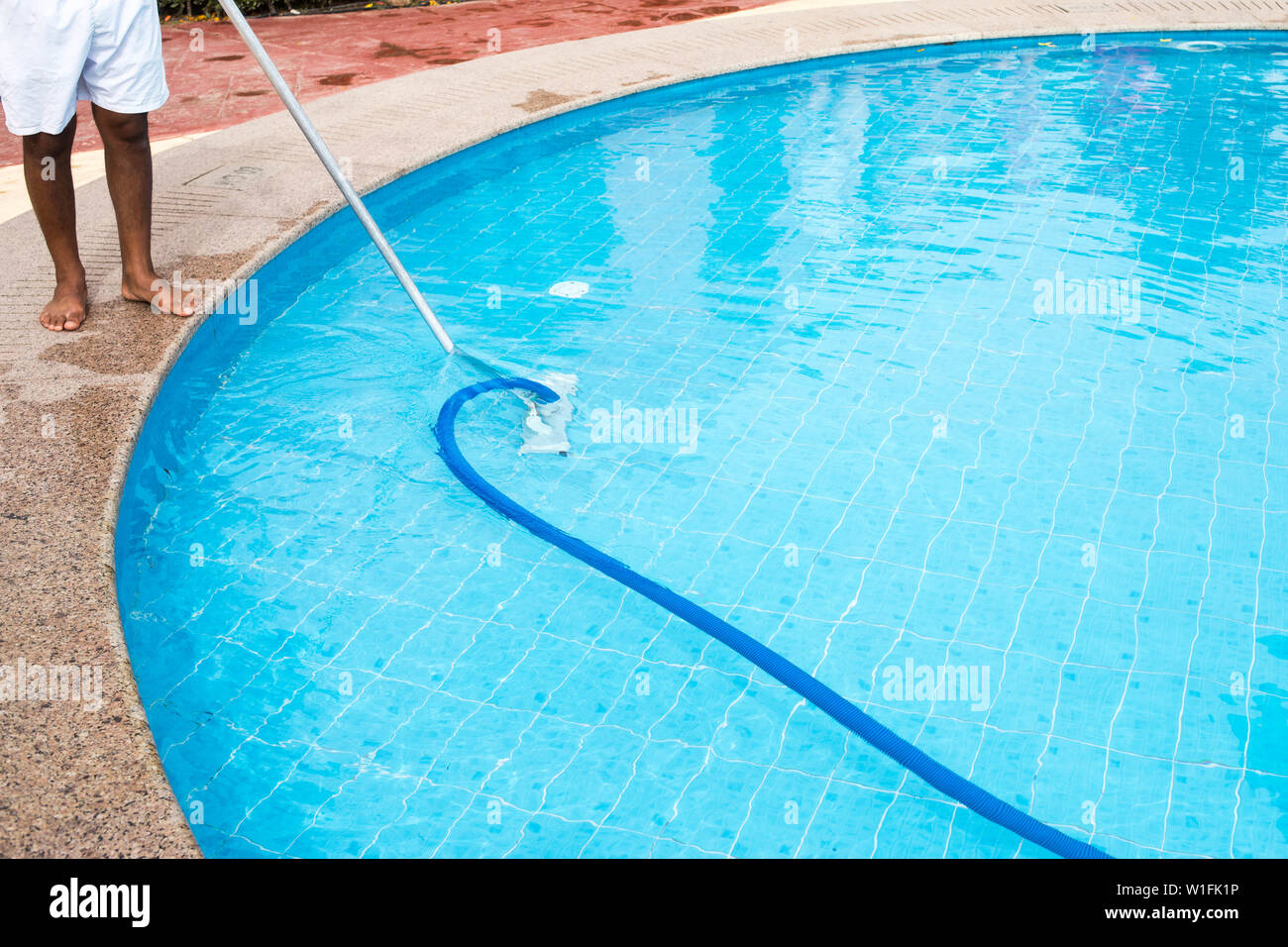 Man cleaning a swimming pool in summer. Cleaner of the swimming pool ...