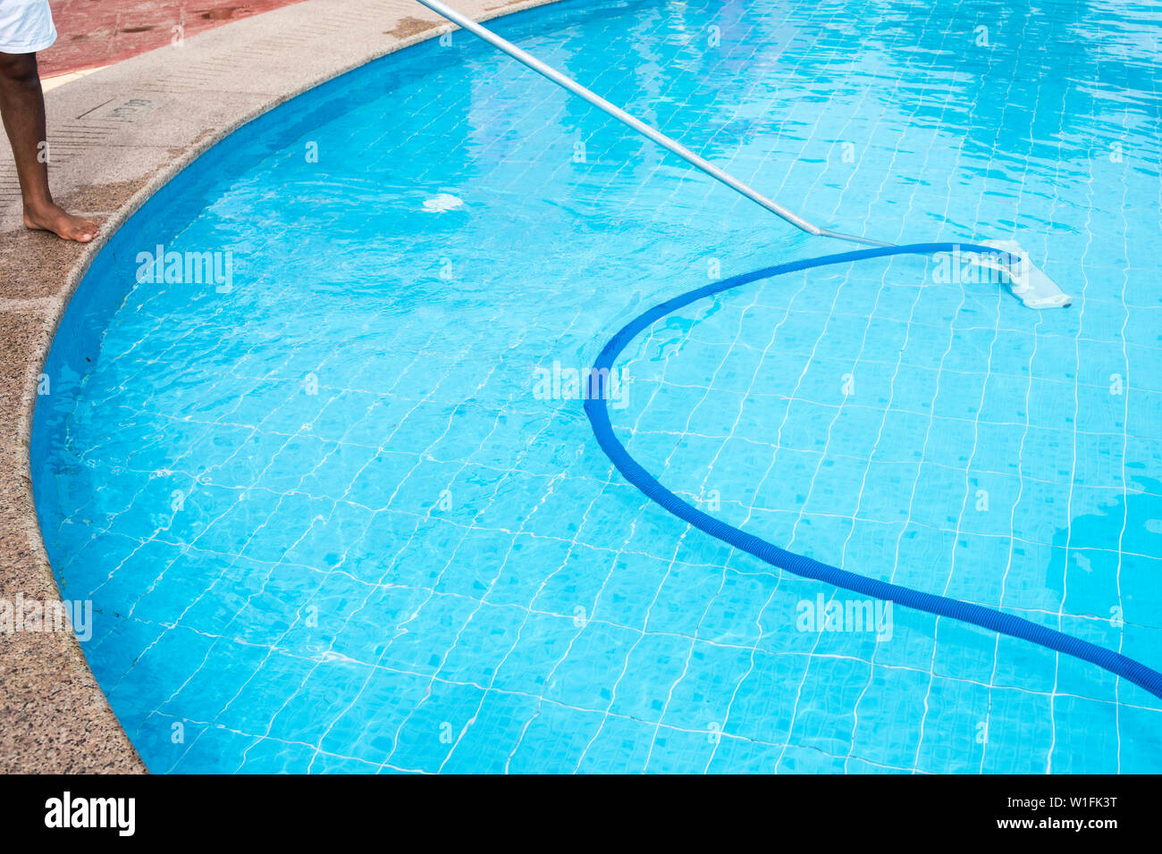 Man cleaning a swimming pool in summer. Cleaner of the swimming pool ...
