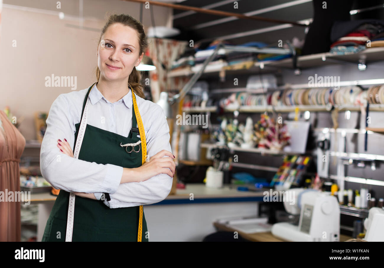Portrait of female seamstress is who is posing in her design studio in ...