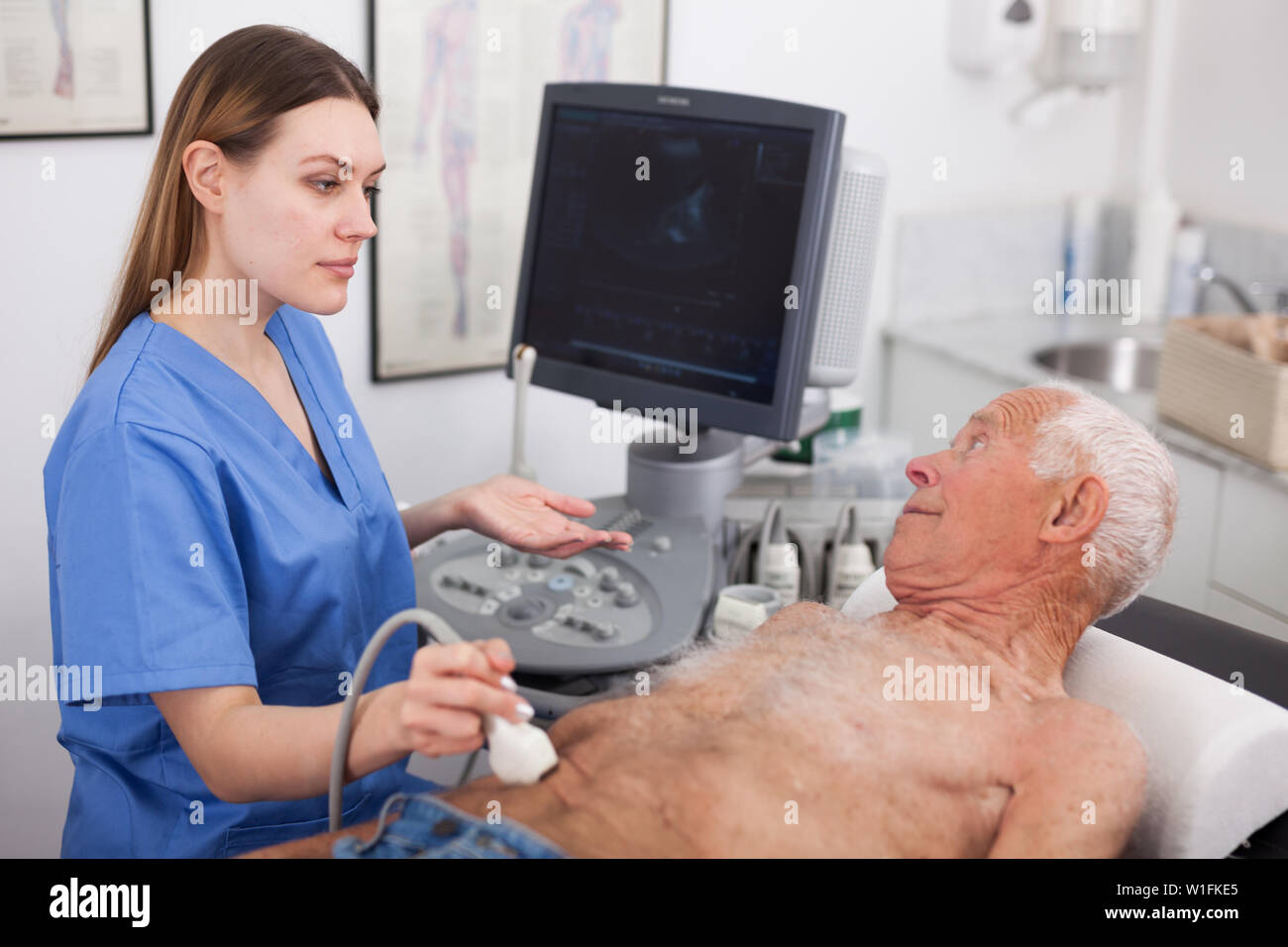 Young woman doctor examination elderly man at abdomen with ...