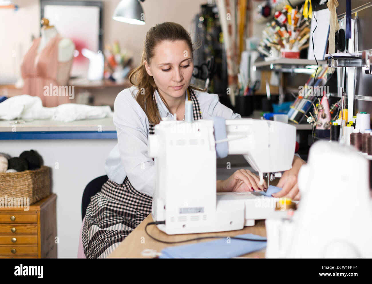 Young woman sewer working with modern sewing machine at workshop Stock ...