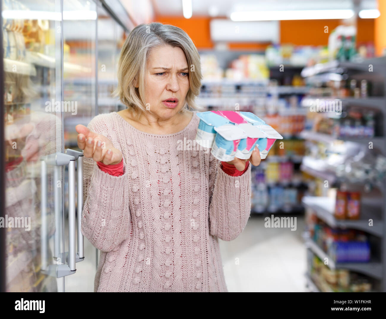 Woman reading product label while choosing groceries in supermarket ...