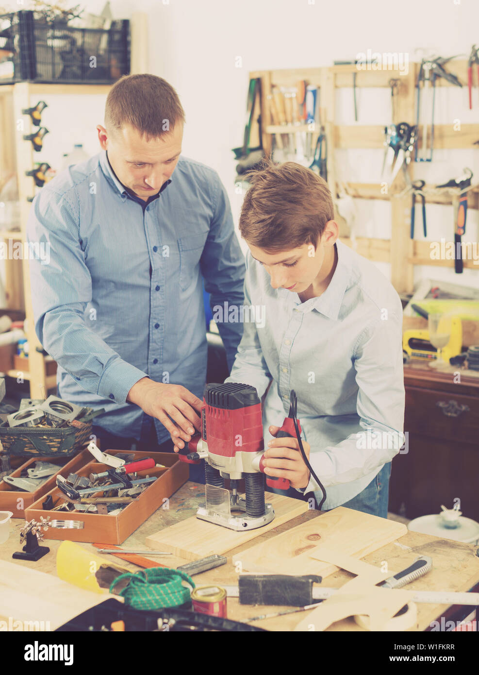 Smiling father and son with wood plank working in sanding machine at ...