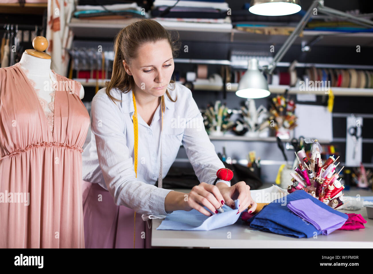 Female seamstress is thinking about new dress for collection of clothes ...