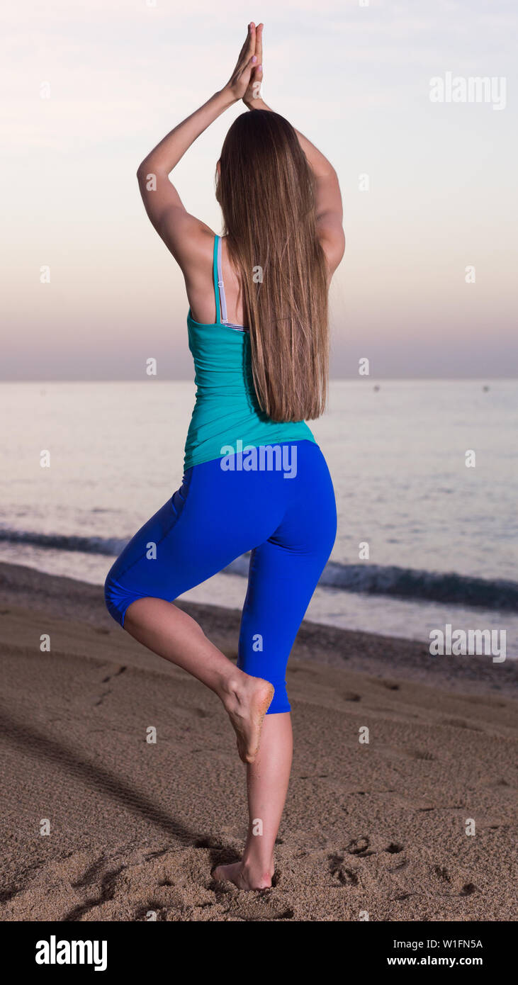 Female 20-25 years old is standing and practicing meditation in blue T ...