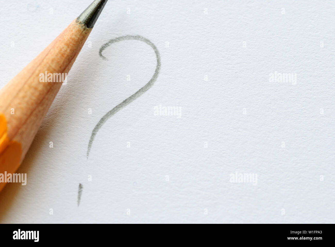 Tip of pencil next to drawn question mark on white paper with copy ...