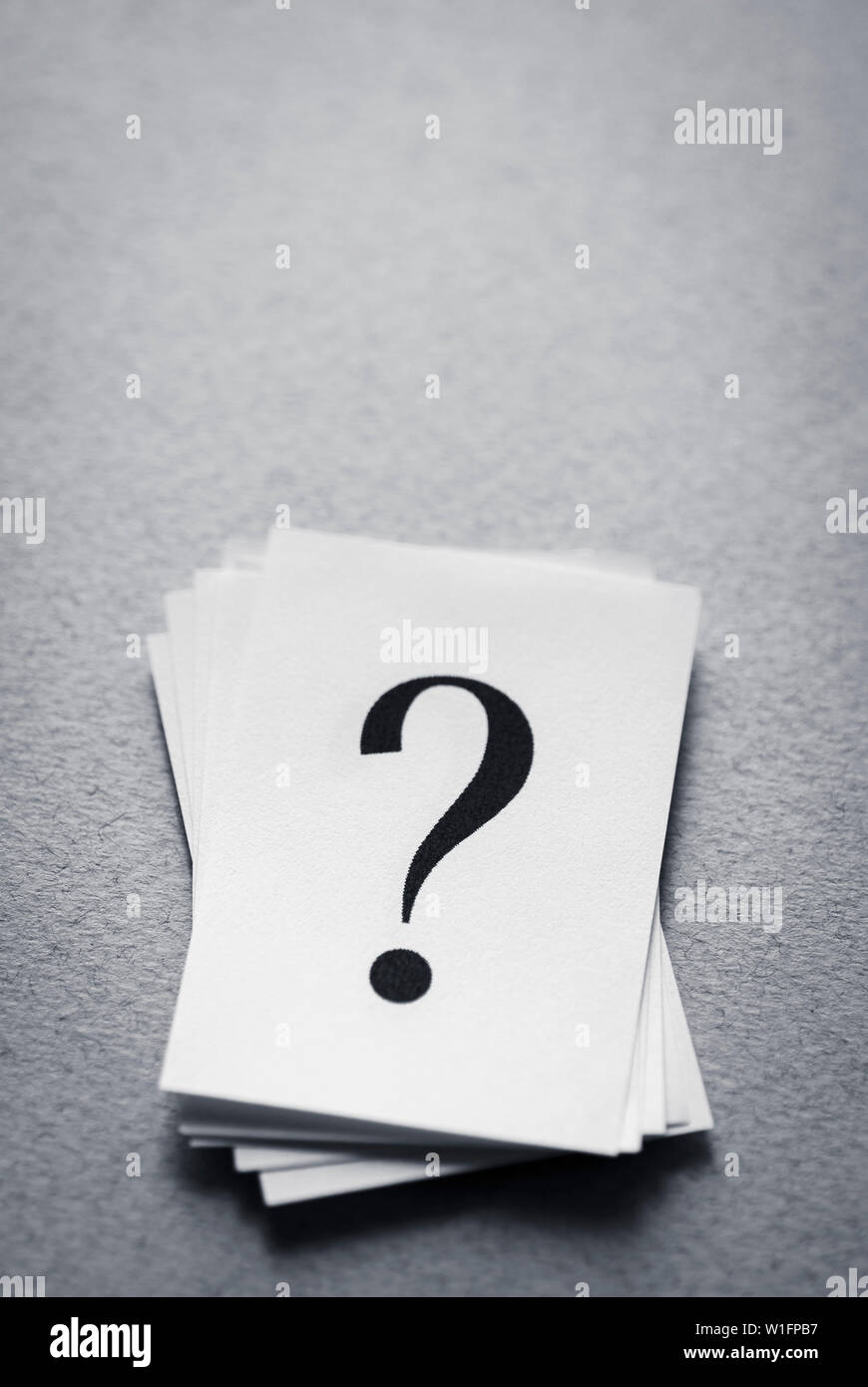 stack of paper cards with a printed question mark on a gray background ...