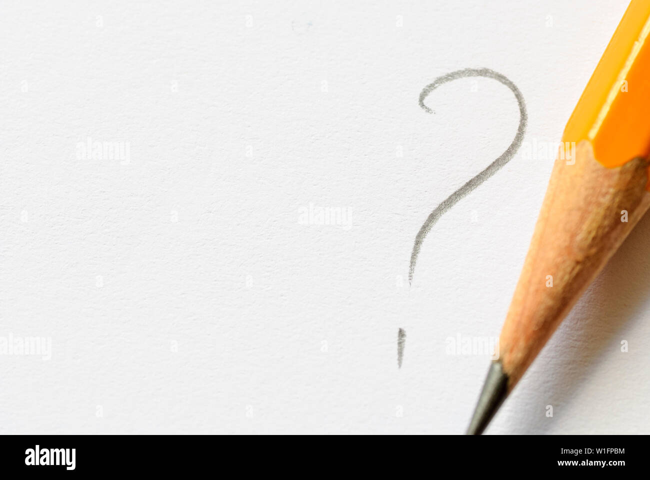 Tip of pencil next to drawn question mark on white paper with copy ...