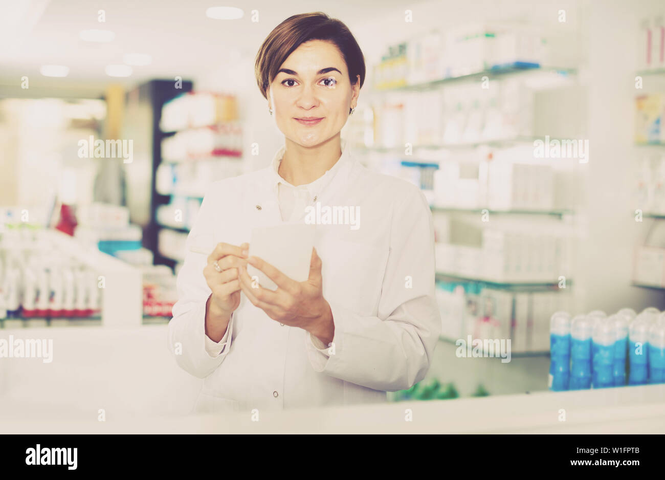Smiling germany female pharmacist checking assortment of drugs in ...