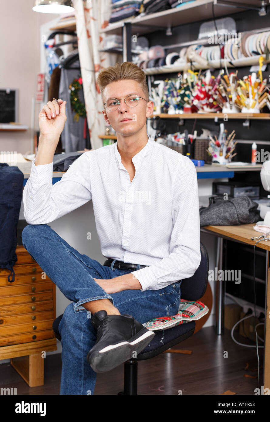 Portrait of blond male dressmaker at his workplace in sewing atelier ...