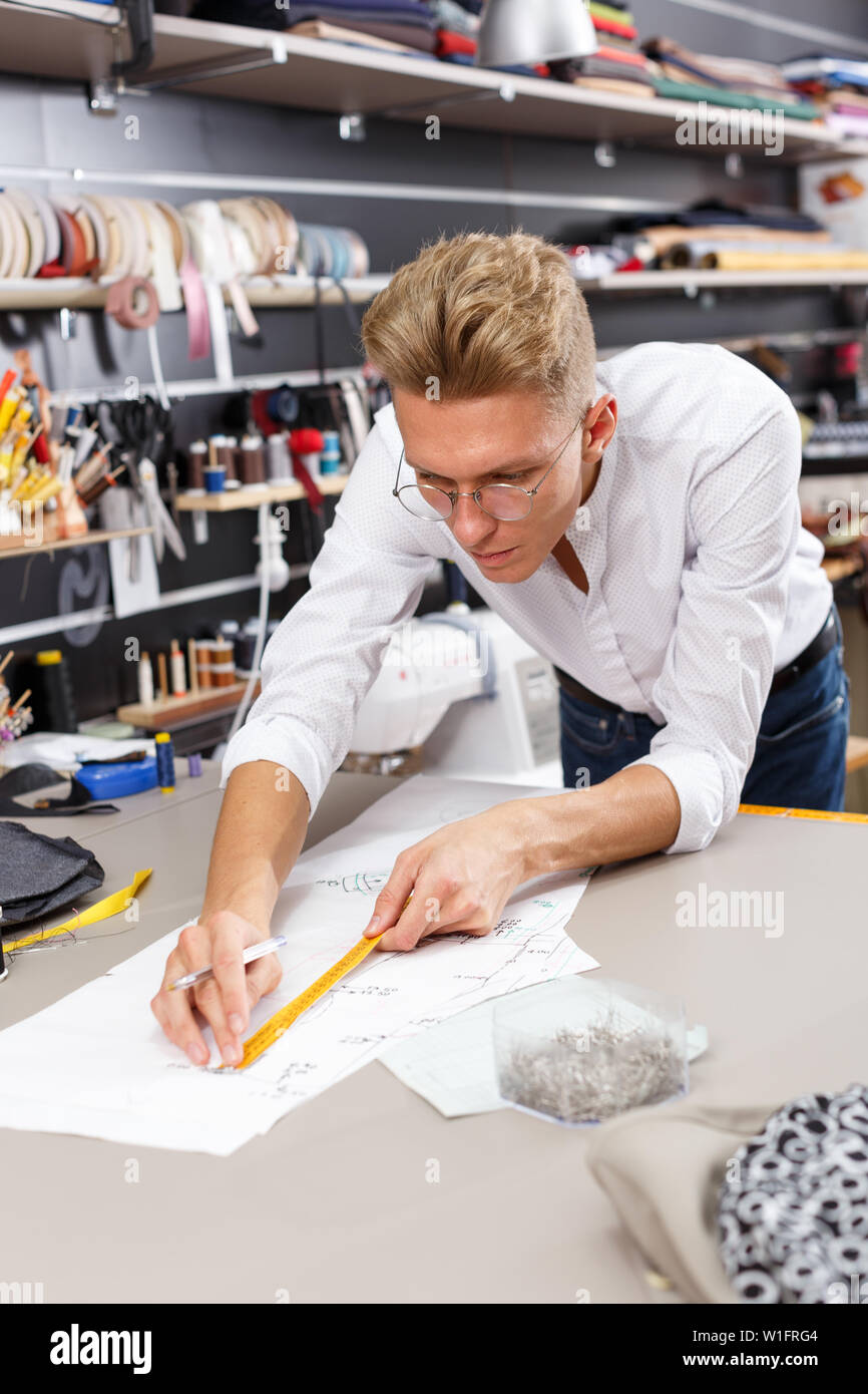 Professional male dressmaker at work – creating pattern at his ...