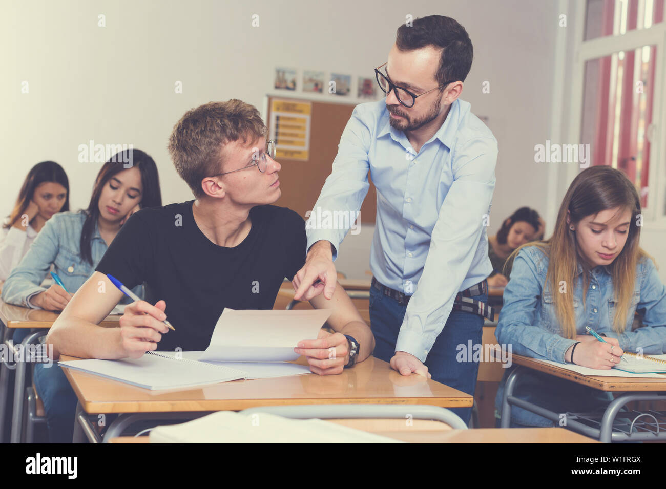 Student is writing test and answer about task and teacher is explaining ...