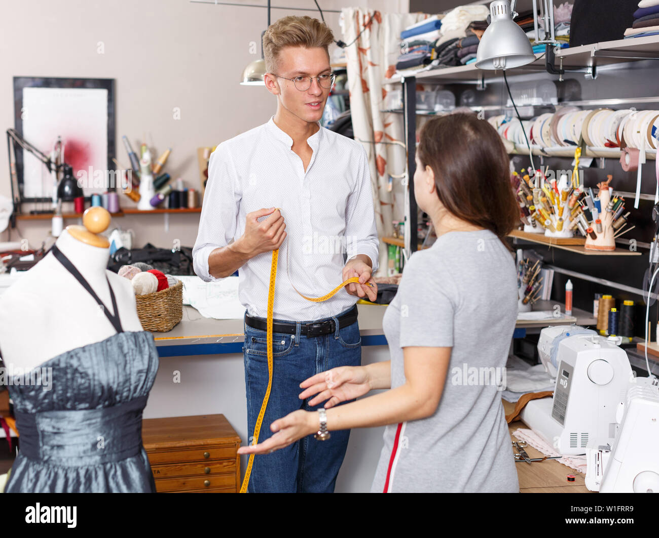 Professional male tailor talking with customer about order details at ...