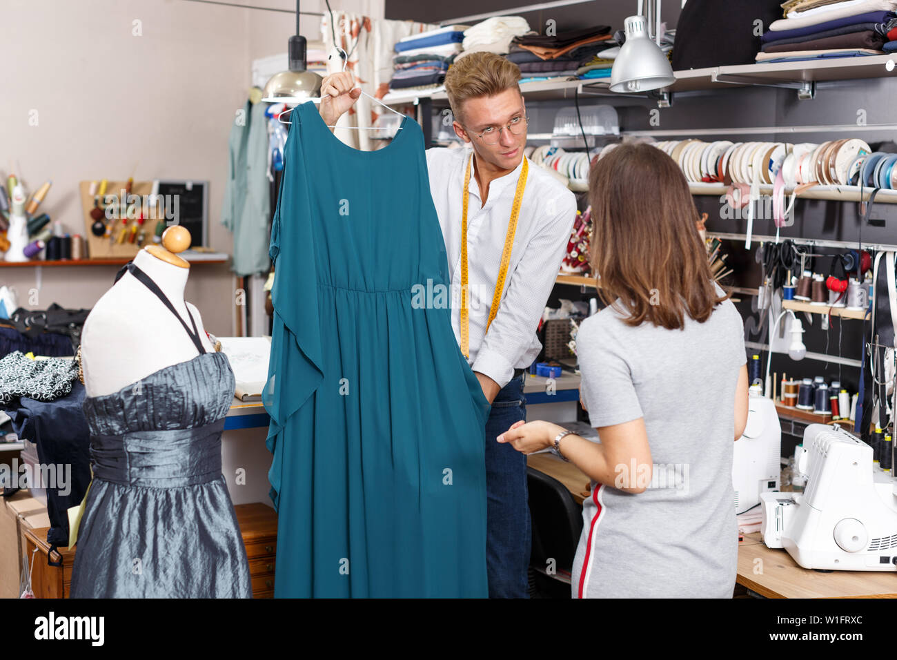 Professional male tailor showing customer dress at sewing atelier Stock ...