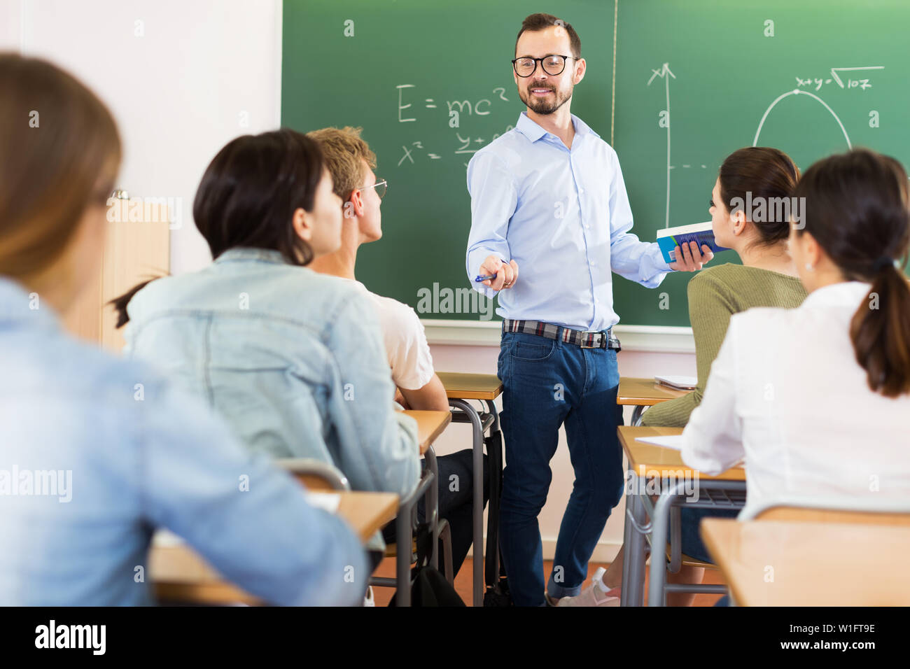 Young male teacher is giving interesting lecture for students during ...