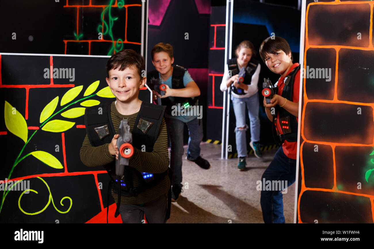 portrait of excited sportive boy aiming laser gun at other players ...