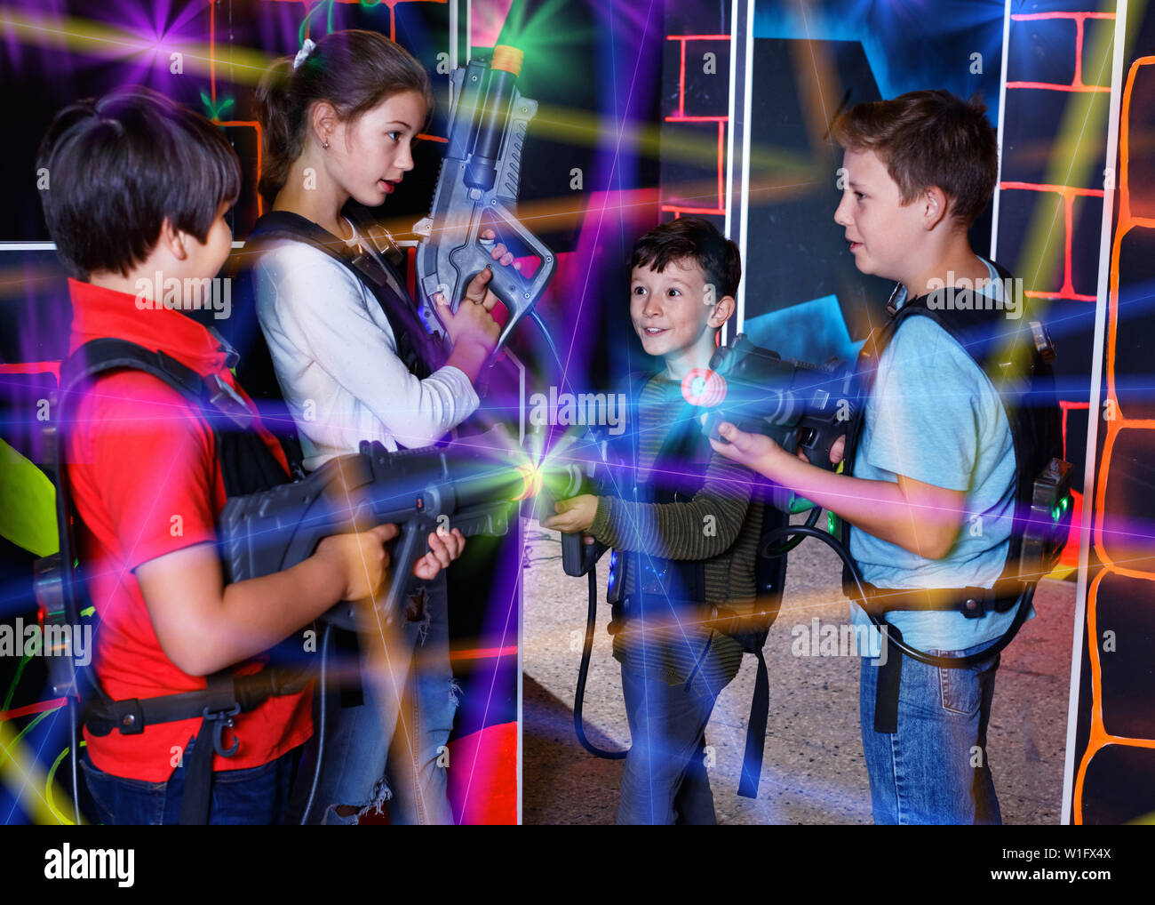 Group of happy cheerful friendly teenagers with laser guns having fun ...