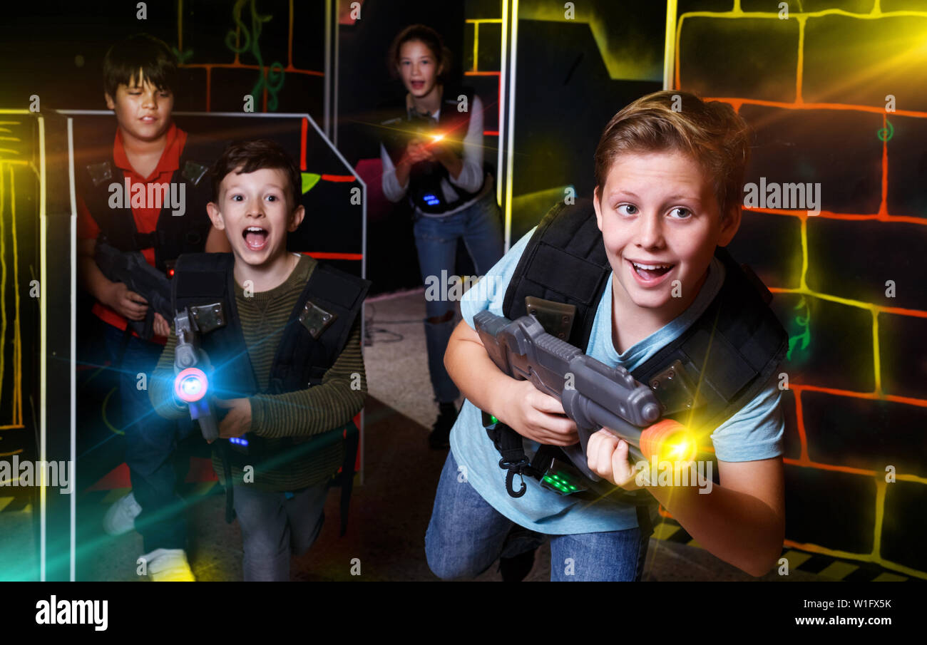 portrait of excited active boy aiming laser gun at other players during ...