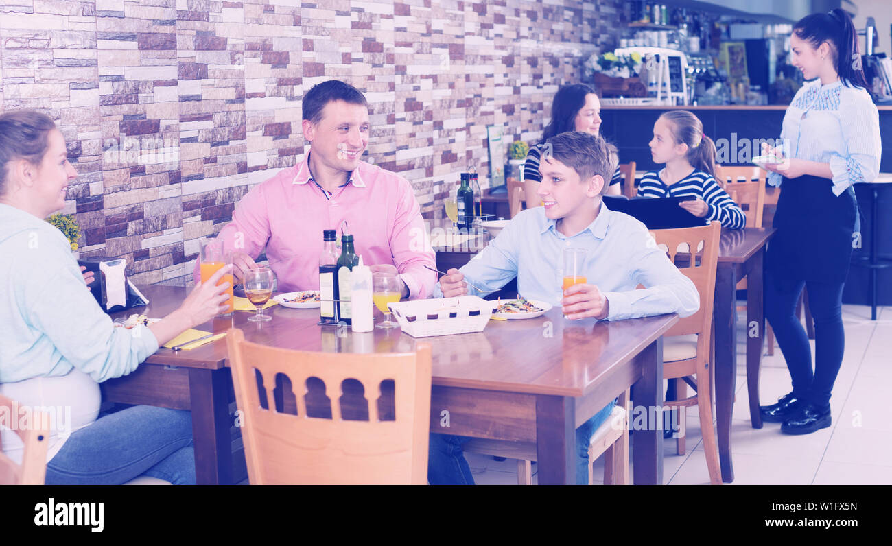Smiling parents with children dining together in modern family ...