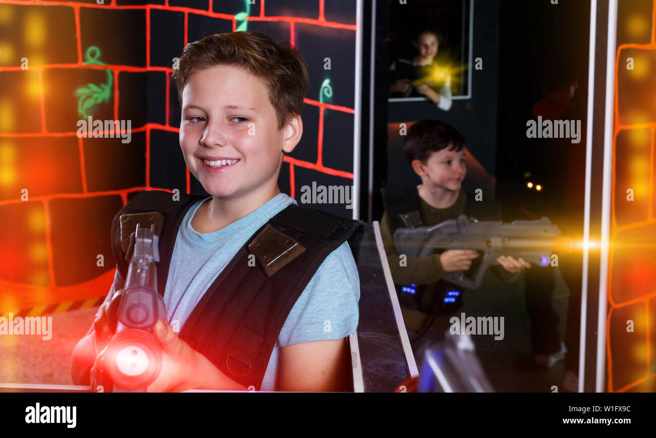 portrait of happy active boy aiming laser gun at other players during ...