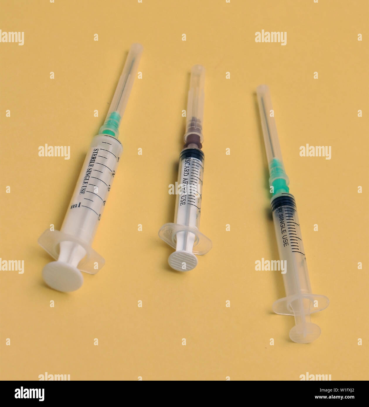 Sterile medical plastic syringes with needles on top closed with a cup ...
