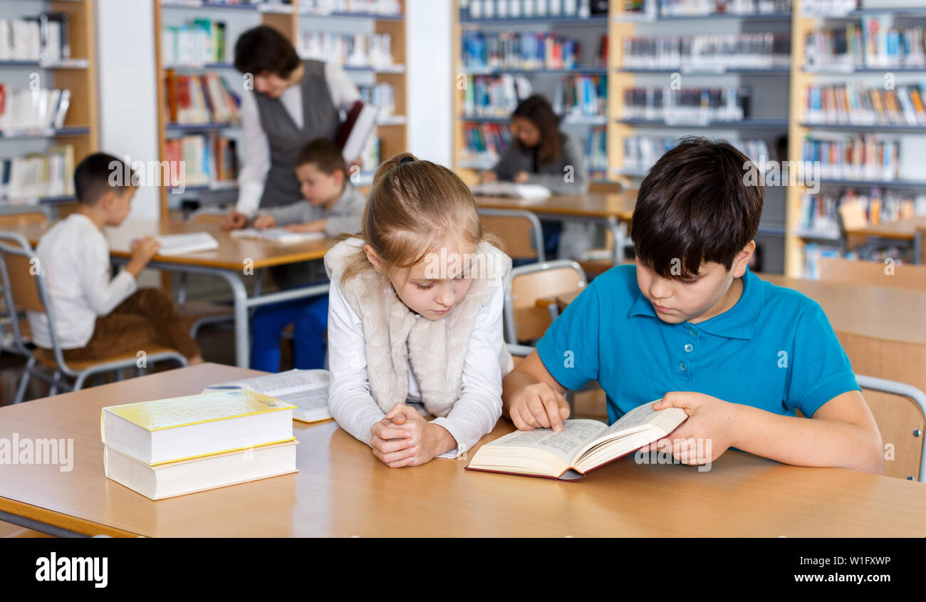 School friends spending time together in library, reading books Stock ...