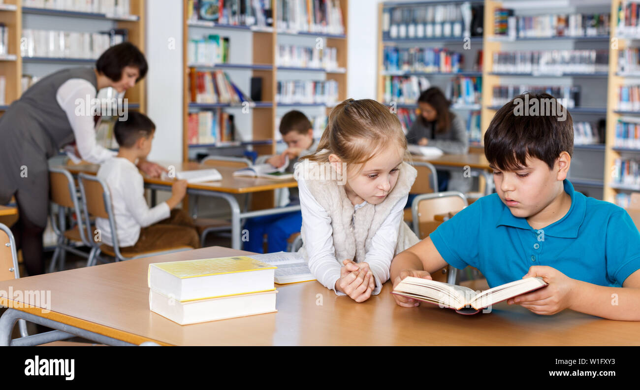 School friends spending time together in library, reading books Stock ...