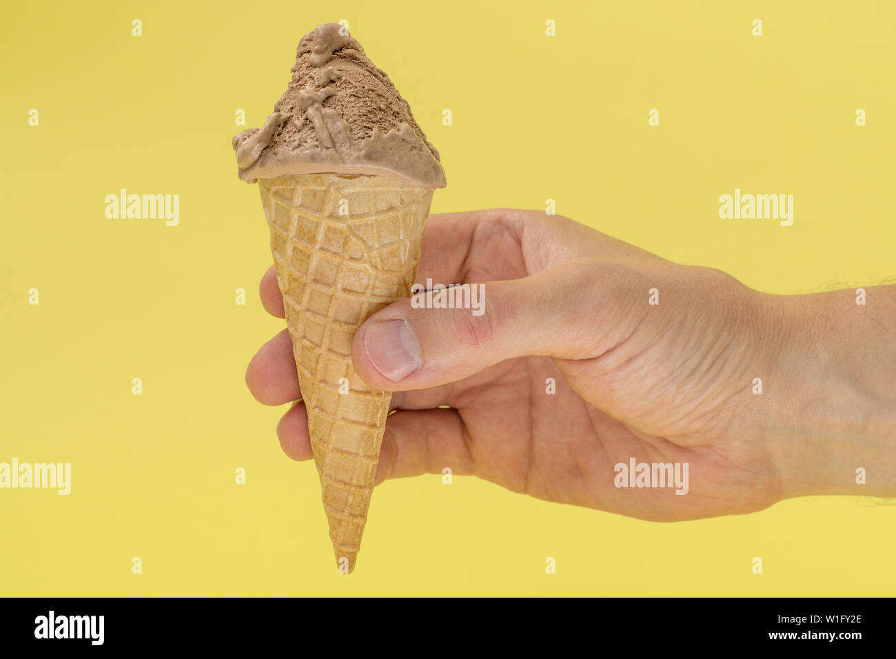 Ice cream cone in hand on yellow background. Summer desserts Stock ...