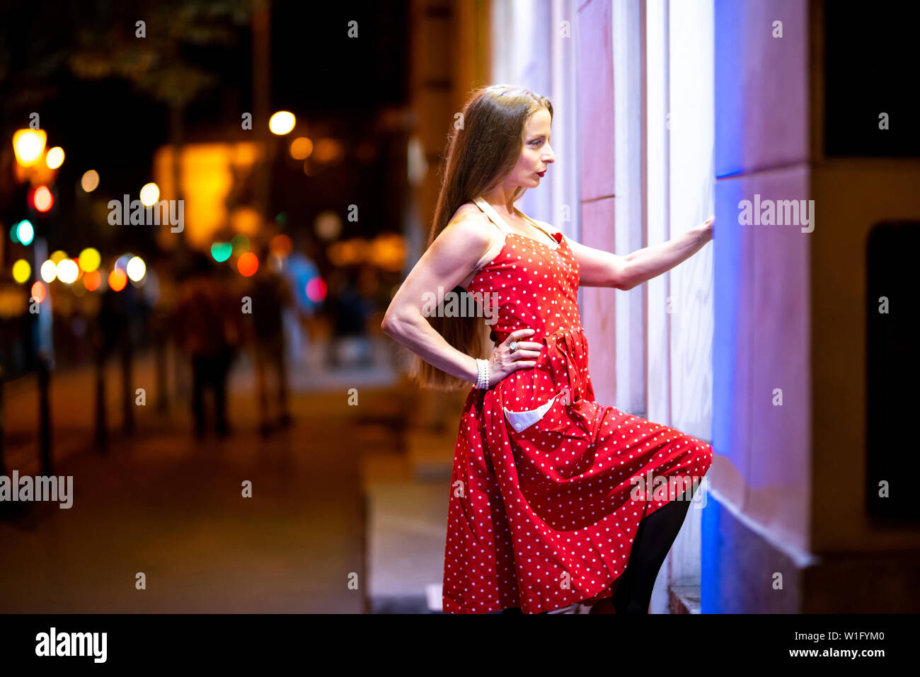 A beautiful mature woman in a red dress checking the storefront at ...