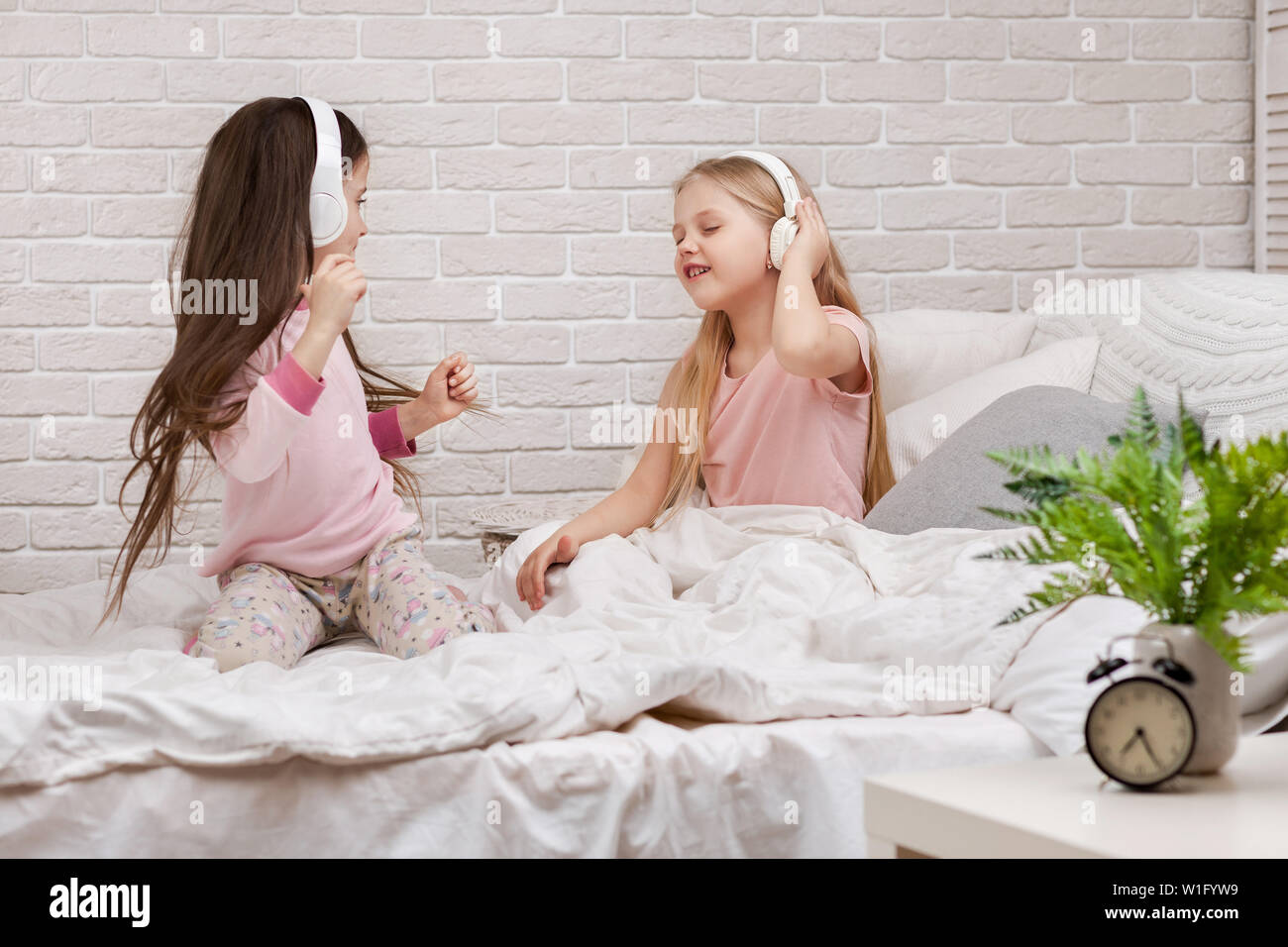 little children girls listening to the music with the headphones and ...