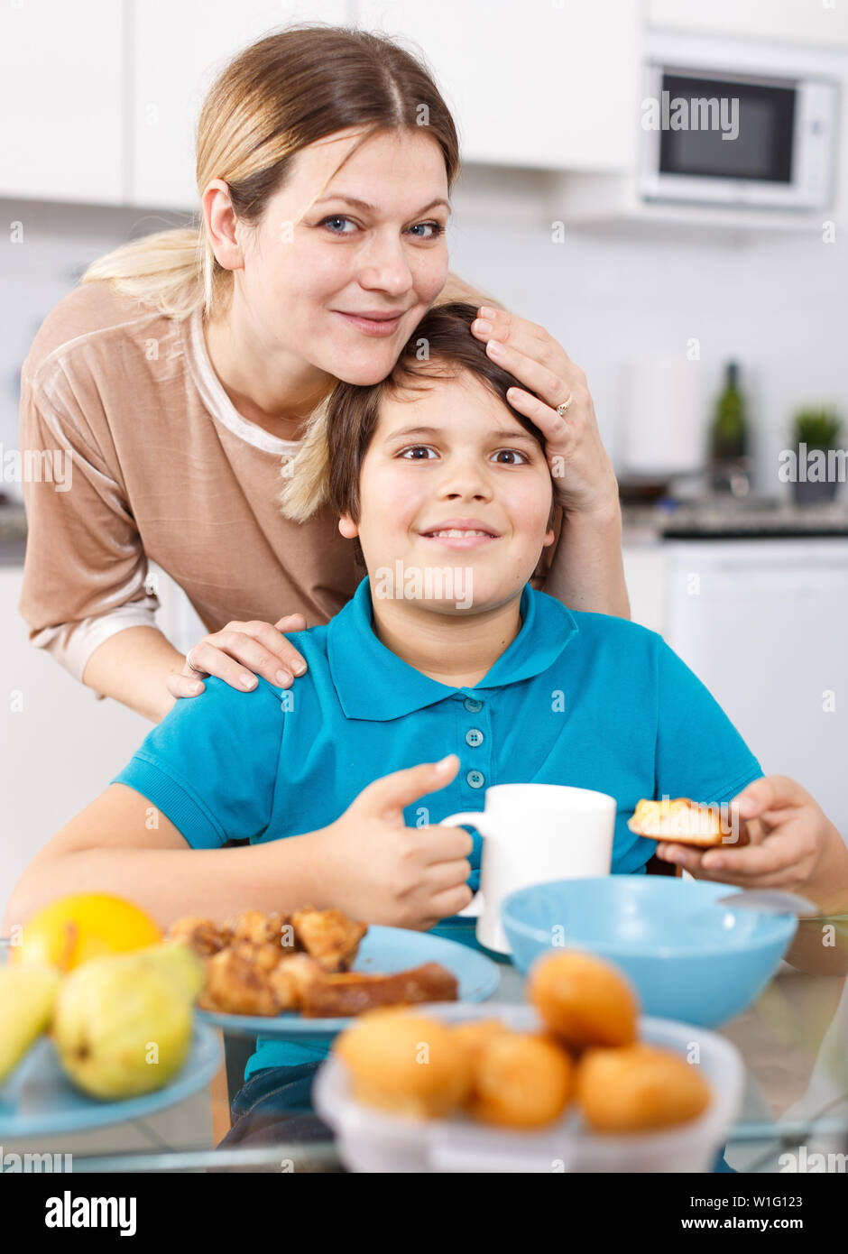 Young woman with tween son enjoying meal at kitchen table Stock Photo ...