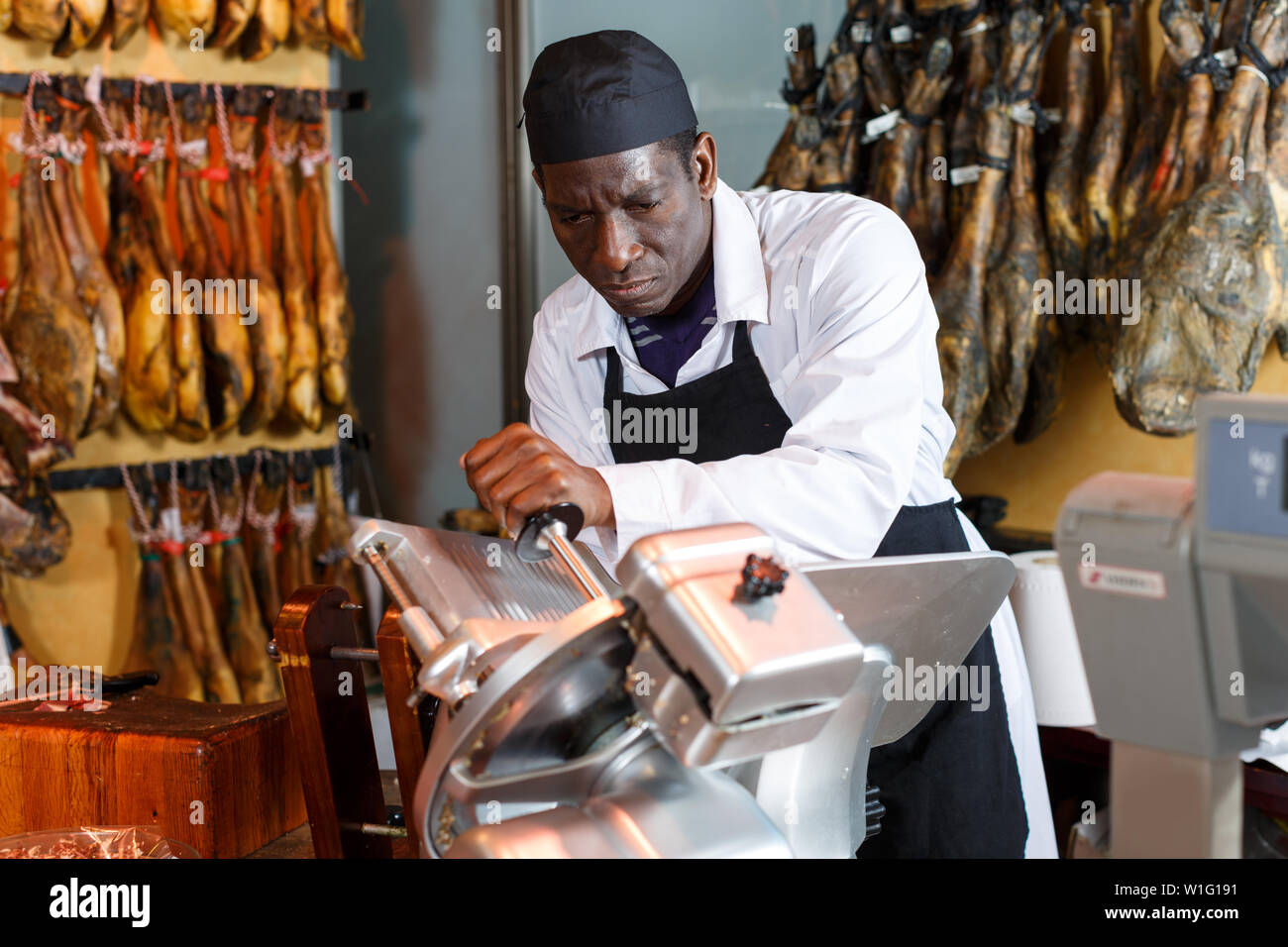 African American butcher preparing meat products for sale in store ...