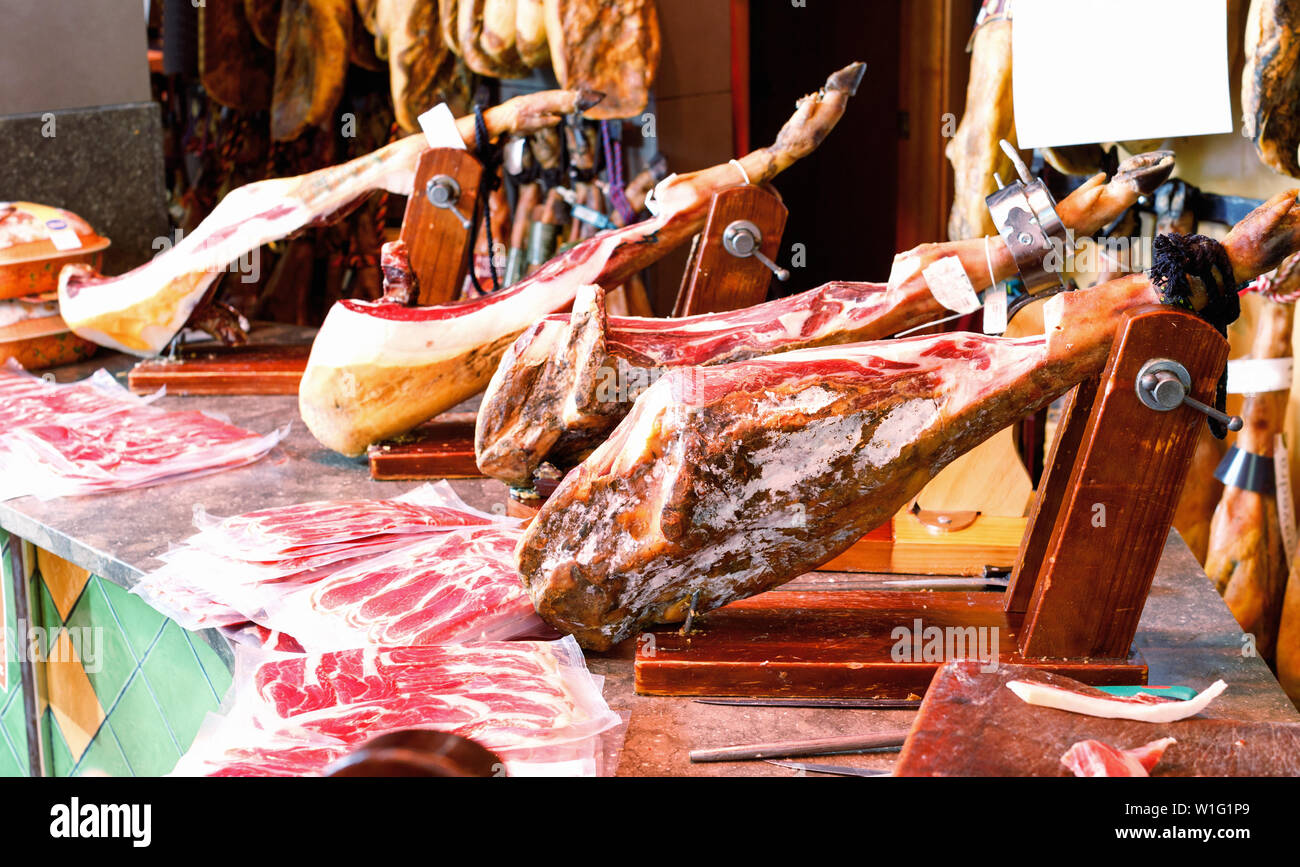 Legs of traditional Spanish jamon fixed on wooden jamoneras ready for ...